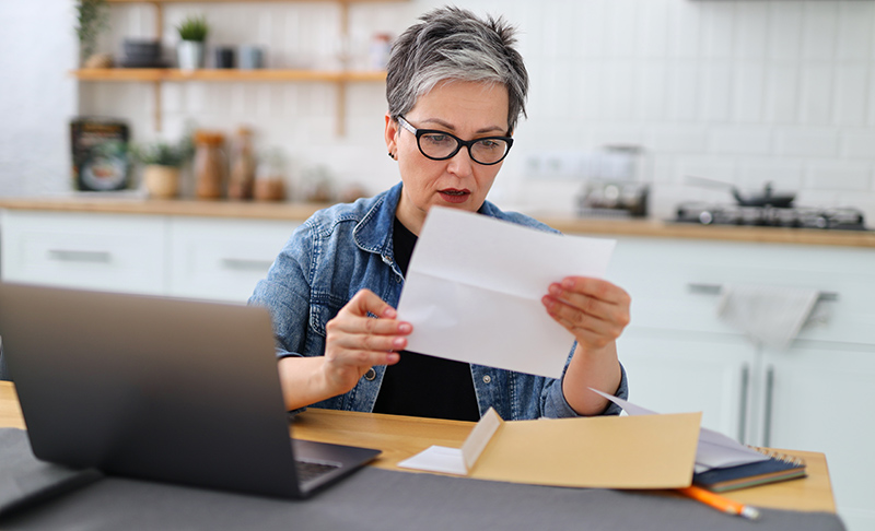 Shocked Woman Holding Letter In Home Interior High Bill For Pay HOA 